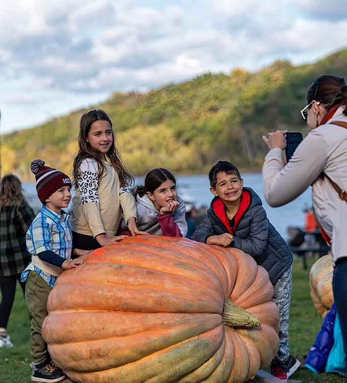 Four kids posing on a giant pumpkin, creating the kind of fall photo that grandparents frame immediately.