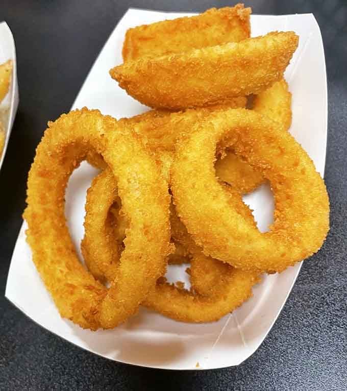 Perfectly golden onion rings stacked like edible architecture, each one promising that satisfying crunch we've been craving since childhood diners.