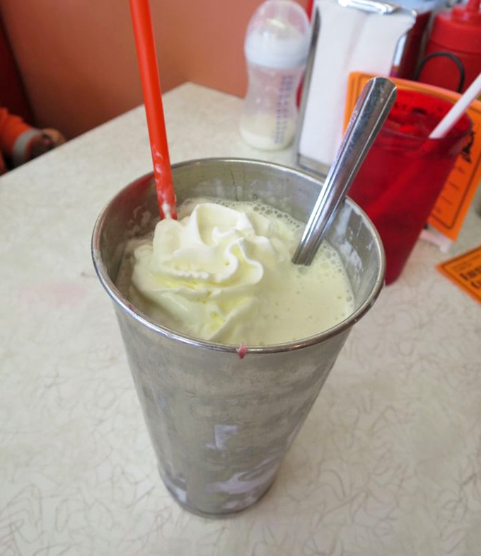 That metal cup holds a hand-dipped shake so thick your straw stands at attention, old-school ice cream parlor perfection.