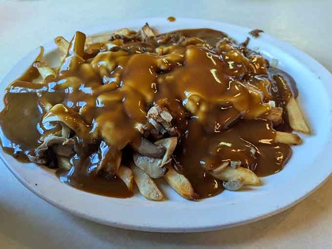 Poutine smothered in gravy so generously you might need a spoon instead of a fork here.