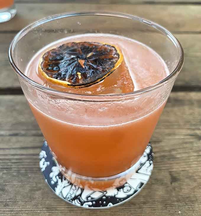 A charred citrus garnish elevates this cocktail from ordinary to Instagram-worthy in one smoky, sophisticated flourish.