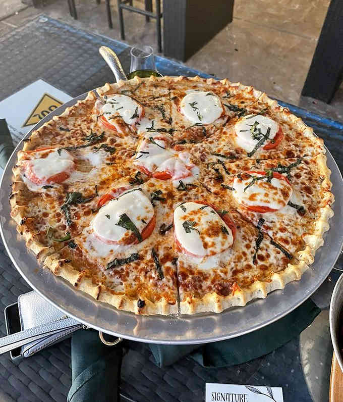 Fresh mozzarella, basil, and tomatoes arranged like edible art on a crispy crust that means business.