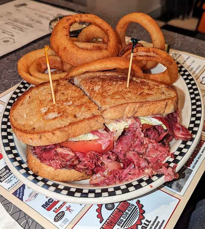That towering pastrami sandwich with onion rings stacked on top is the kind of lunch that requires a nap afterward.