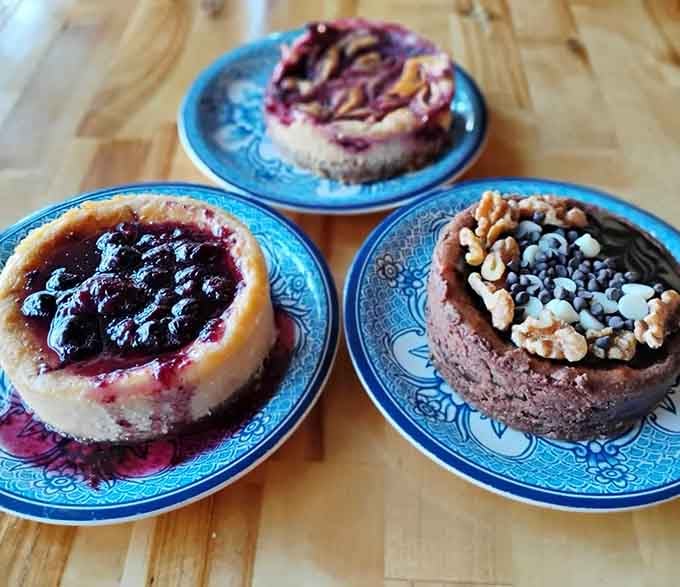 Three mini cheesecakes on blue plates, because choosing just one flavor is for people with more willpower.