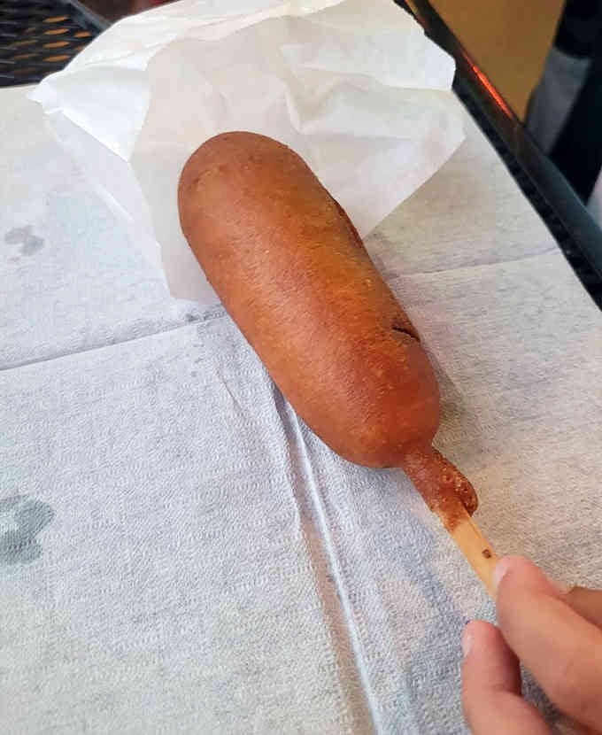 The corn dog on a stick, a nostalgic throwback that tastes exactly like summer should, no apologies necessary.
