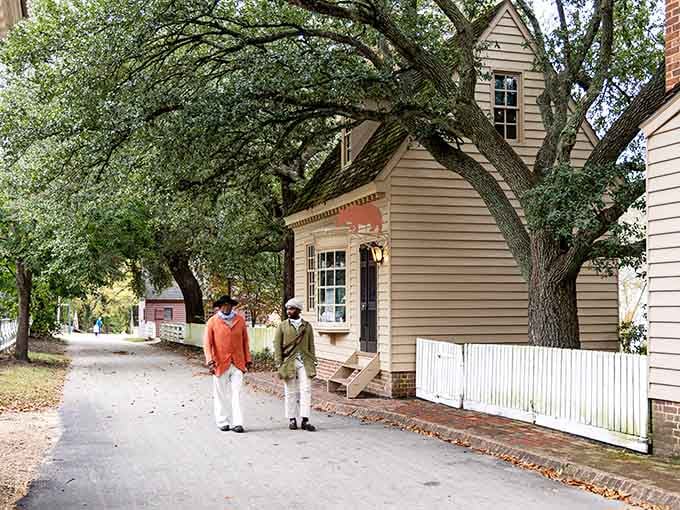 Period-costumed interpreters strolling beneath ancient oaks, casually making the 1700s look more stylish than your entire wardrobe combined.