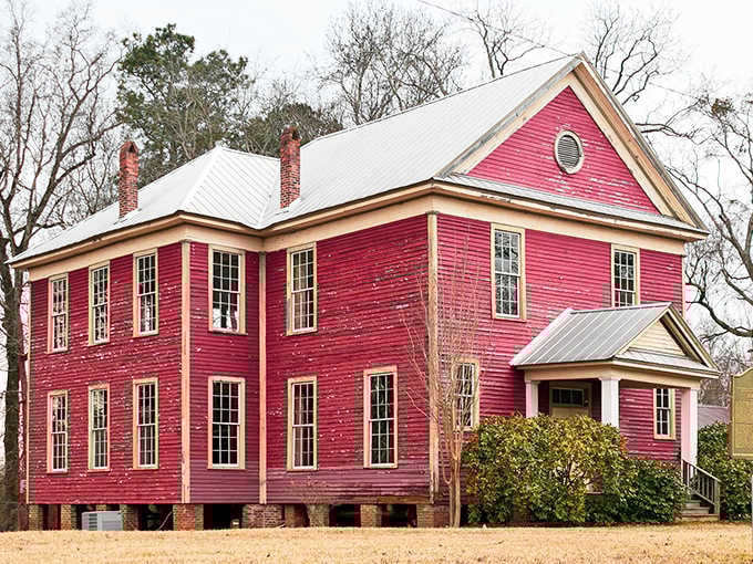 This pink schoolhouse stands proud despite peeling paint, its faded grandeur a testament to better days long since passed.