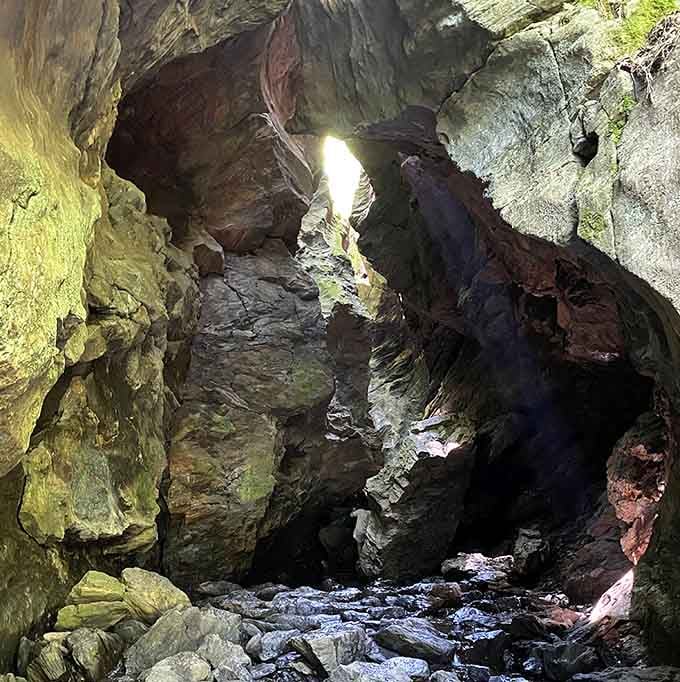 Step inside where light pierces the darkness, revealing rock walls painted in sunset hues by mineral deposits.