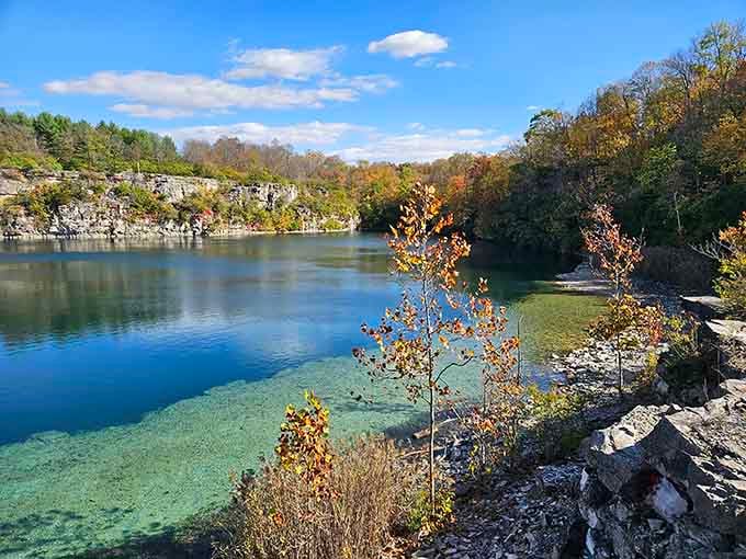 Autumn foliage framing turquoise water creates contrast so stunning, your camera might actually applaud you for capturing it.