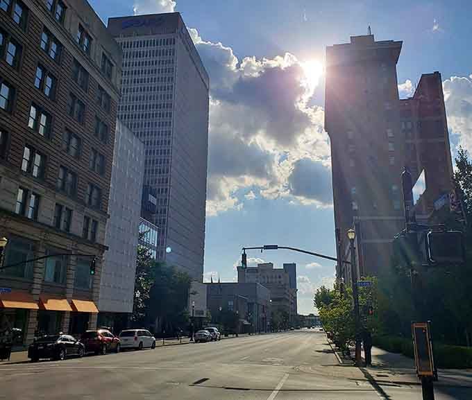 Dramatic clouds frame historic buildings where sunlight breaks through like nature's own spotlight on urban beauty.