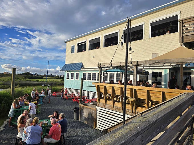 Colorful outdoor seating and cheerful umbrellas create the perfect spot for watching boats glide through the marshlands.