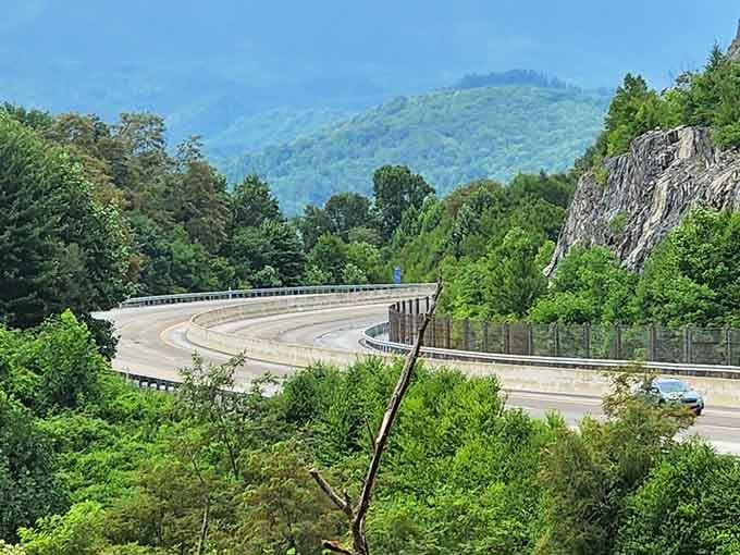 Ancient rock faces stand sentinel beside the highway as it swoops through the valley toward those hazy distant peaks.