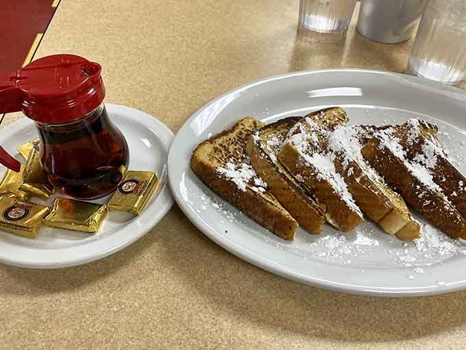 French toast dusted with powdered sugar and served with syrup&mdash;breakfast done right, no frills, just deliciousness that makes mornings worth waking up for.