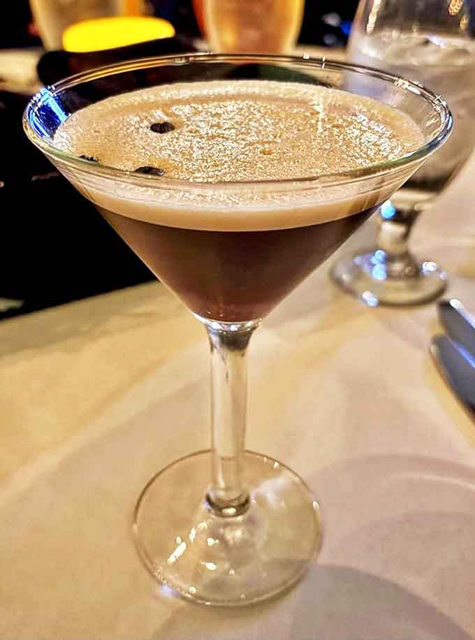 An espresso martini with three coffee beans floating on top: dessert and after-dinner drink combined.