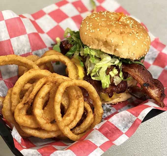 That sesame seed bun towers over bacon, cheese, and perfectly golden onion rings begging to be photographed first, eaten second.