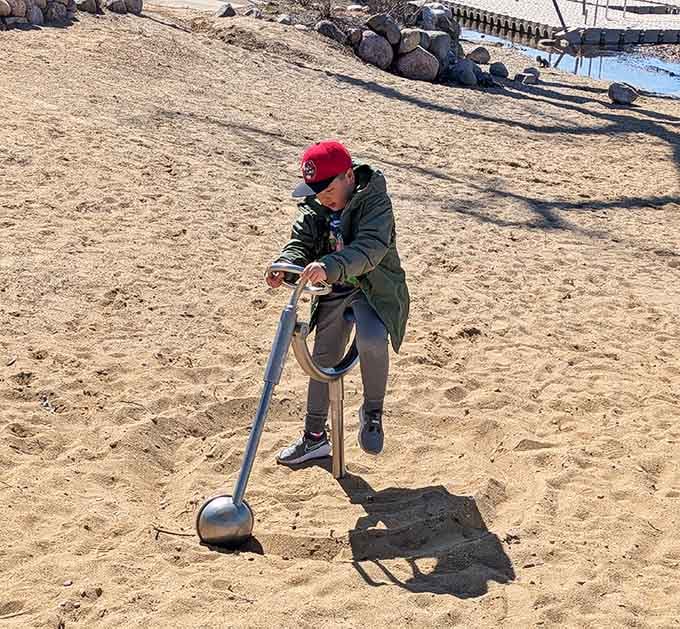 Young excavator operates heavy machinery with the focused determination of someone building tomorrow's sandcastle empire from scratch.