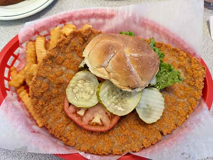 The breaded tenderloin sprawls beyond the bun's borders like delicious edible architecture defying all reasonable expectations.