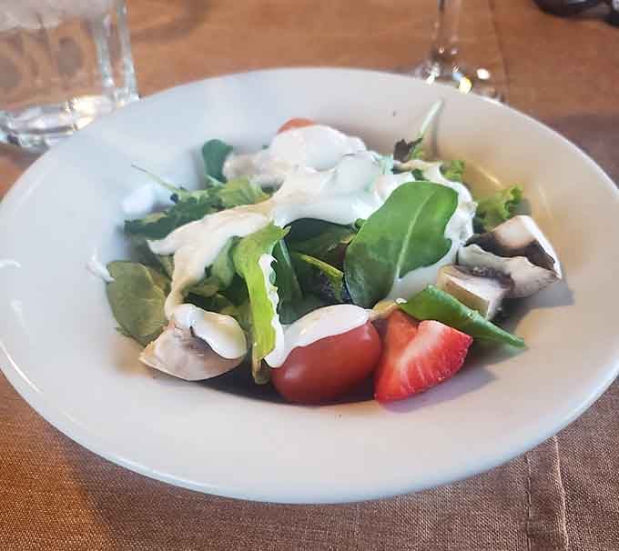 Fresh greens with strawberries and creamy dressing offer a lighter option, though you're probably here for the other stuff.