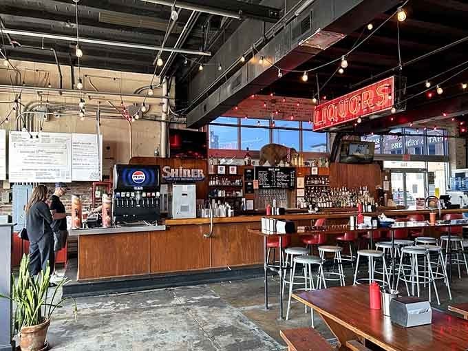 The bar area beckons with that glowing neon promise, where craft cocktails and bourbon flow freely all day.