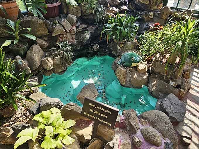 A turquoise wishing well nestled among rocks and greenery adds whimsical charm to this already enchanting castle grounds.