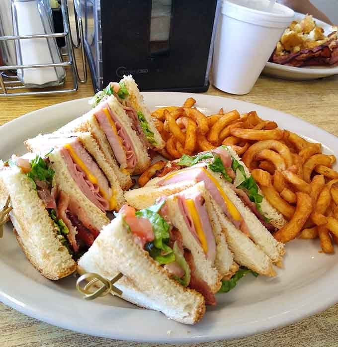 This towering club sandwich comes stacked high with meat, cheese, and curly fries that deserve their own fan club.