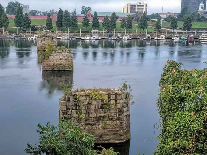 More bridge remnants dot the river like broken teeth, each pillar a tombstone marking where prosperity used to cross these waters regularly.