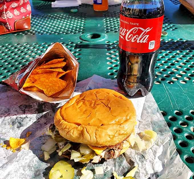 The holy trinity of burger perfection: juicy patty, crispy chips, and an ice-cold Coca-Cola in the sunshine.