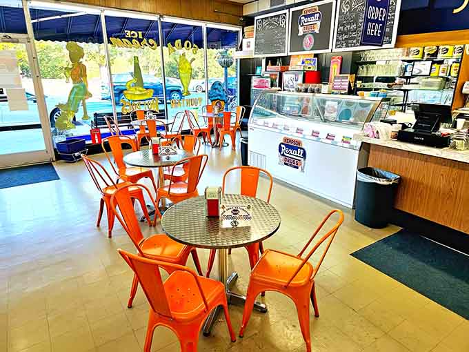Those cheerful orange chairs practically beg you to sit down, relax, and forget what year it actually is.