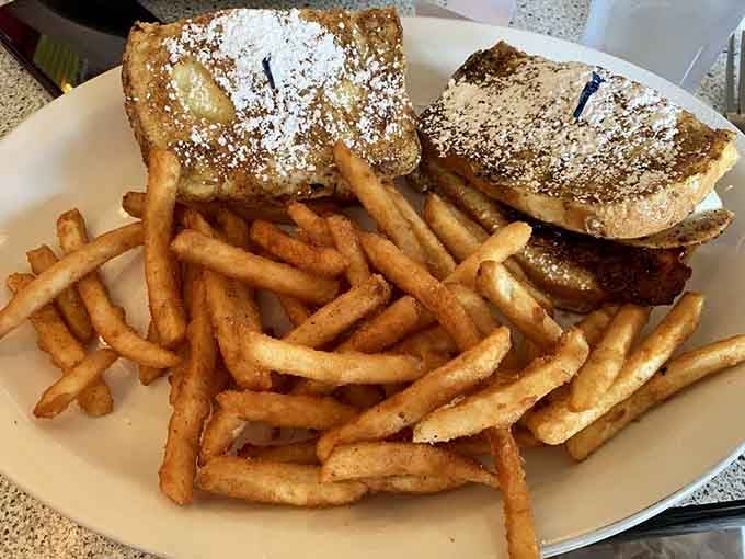 French toast dusted with powdered sugar and served with fries because sometimes breakfast needs a little lunch energy too.