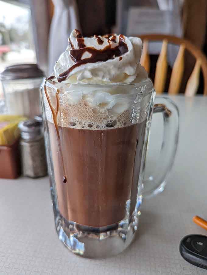Hot chocolate topped with whipped cream and chocolate drizzle because sometimes more is actually more, not less.