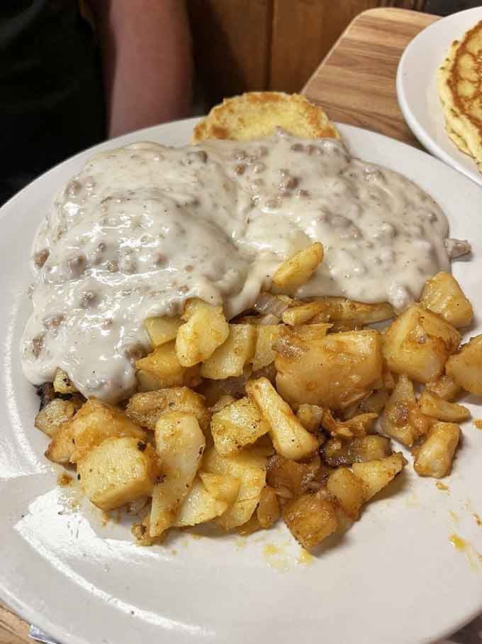 Sausage gravy cascading over biscuits like a creamy avalanche of pure comfort food joy.