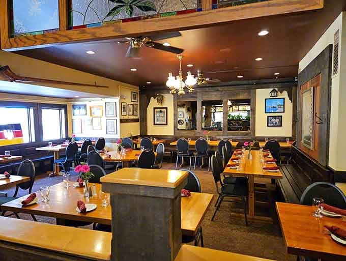 Natural light streams through windows onto wooden tables set with wine glasses, creating an inviting European atmosphere.