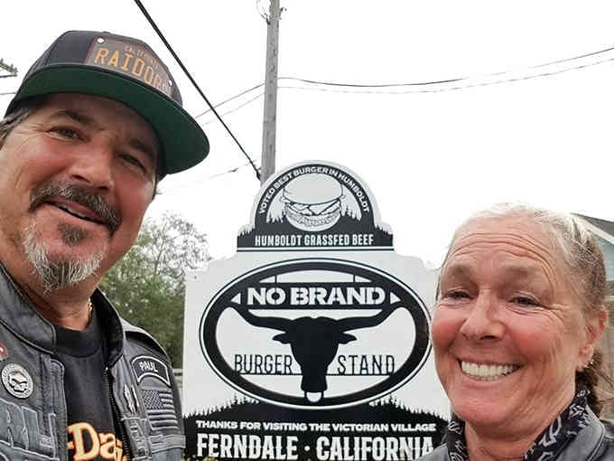 Happy travelers pose with the sign, proving that finding great burgers brings more joy than any tourist trap ever could.