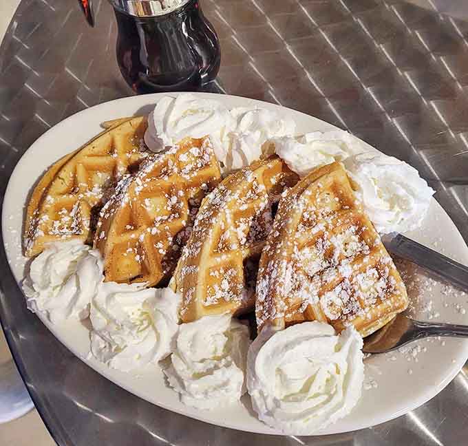 Waffles topped with whipped cream and powdered sugar deliver pure breakfast bliss that photographs beautifully but tastes even better.