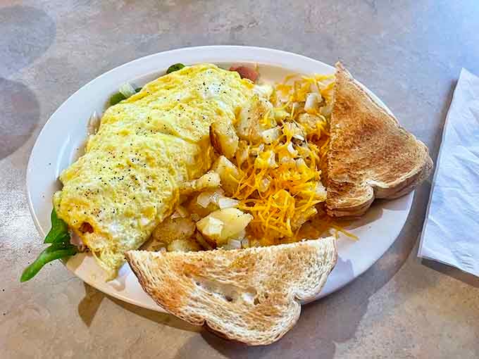 A fluffy omelet with crispy hash browns and toast represents breakfast done the way it should be, generous and delicious.