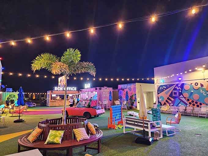 Palm trees, string lights, and that pink-and-purple glow create an atmosphere straight out of a fever dream.