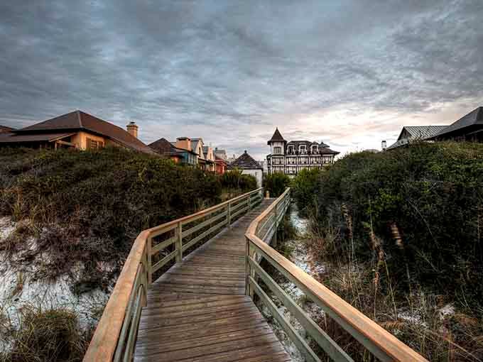 Wooden boardwalks wind through protected dunes toward storybook homes, proving the journey can be as enchanting as the destination.