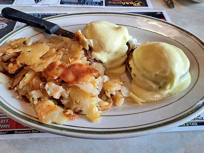 Eggs Benedict with hollandaise that flows like liquid gold over perfectly poached eggs and crispy hash browns.