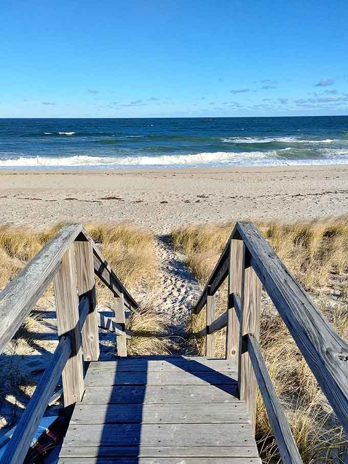 Wooden stairs descend through beach grass to sand and surf, because paradise should always require a little bit of effort.