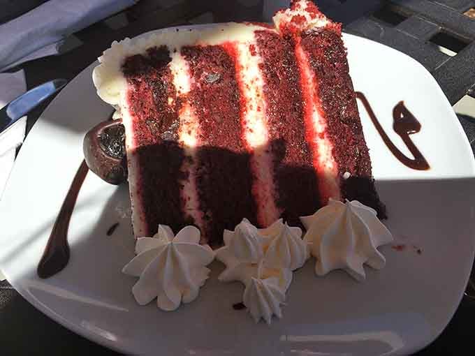 Red velvet cake towering high enough to require architectural planning before your first forkful.