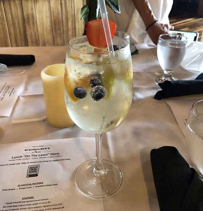 White sangria with blueberries floating like tiny flavor bombs, refreshing enough to make you forget it's technically still morning.