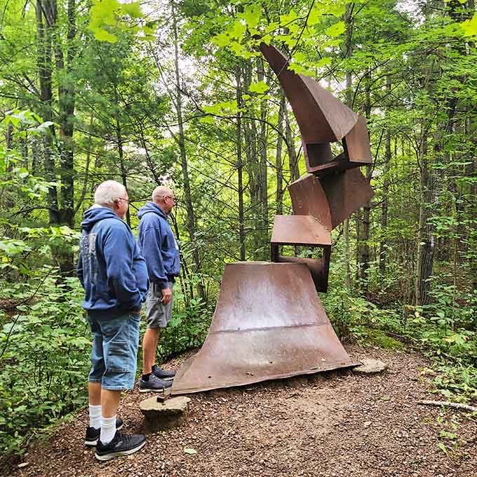 Two visitors contemplate this towering rust sculpture, probably debating what it means over their morning coffee.