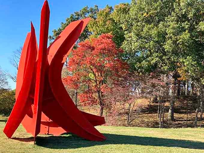 Bold red angles cutting through autumn colors, a sculpture that refuses to blend into the background.