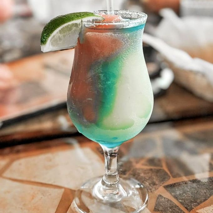 This rainbow margarita looks like a vacation in a glass, minus the sunburn and airport security lines.