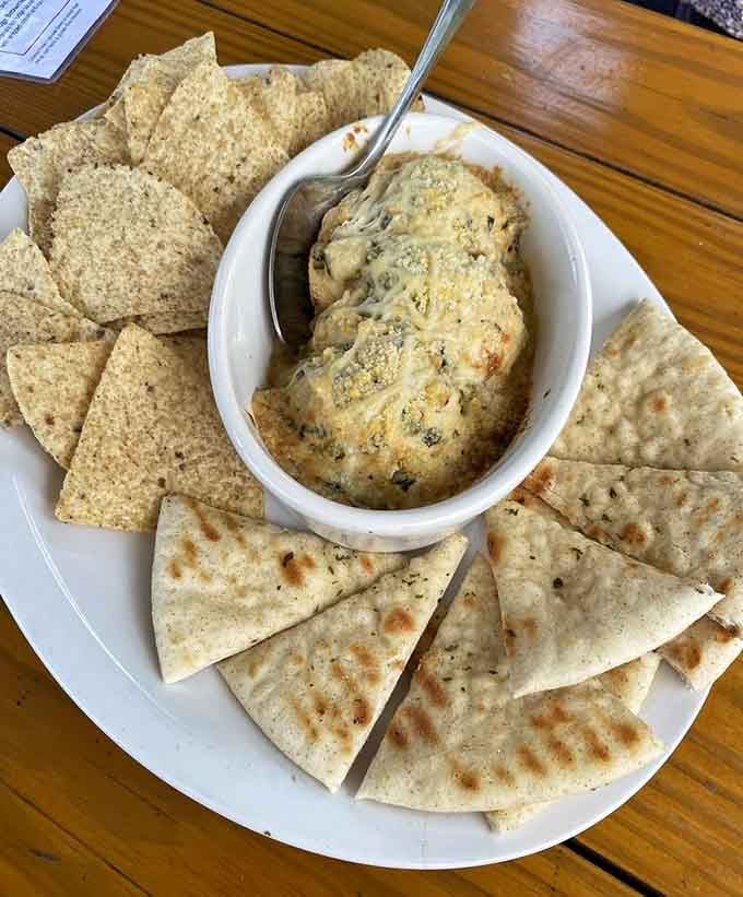 Creamy artichoke dip surrounded by warm pita and crispy chips solves the age-old "what should we share" debate instantly.