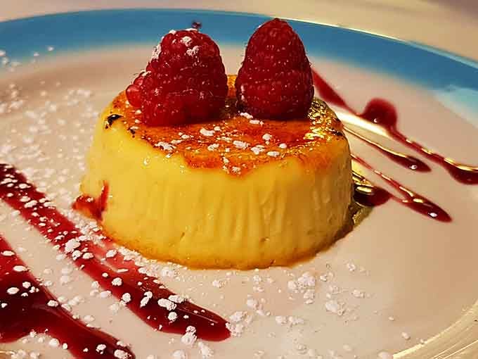Cr&egrave;me caramel crowned with fresh raspberries, a sweet finale that proves dessert is always worth the Revolutionary effort.