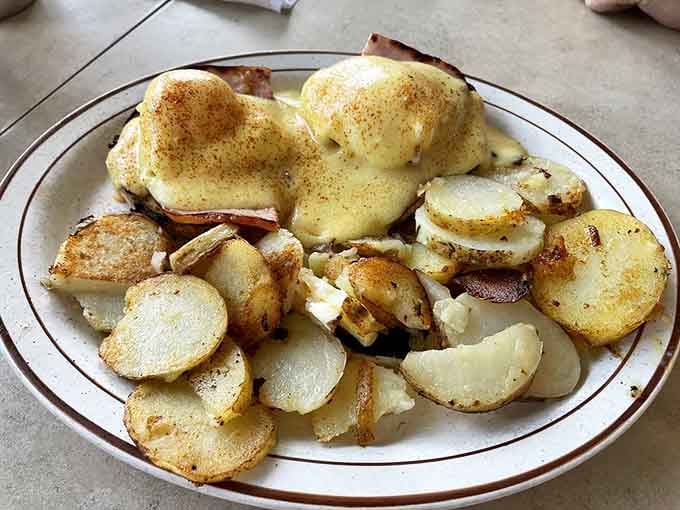 Eggs Benedict done right, with hollandaise sauce flowing like liquid gold over perfectly poached eggs and crispy potatoes.