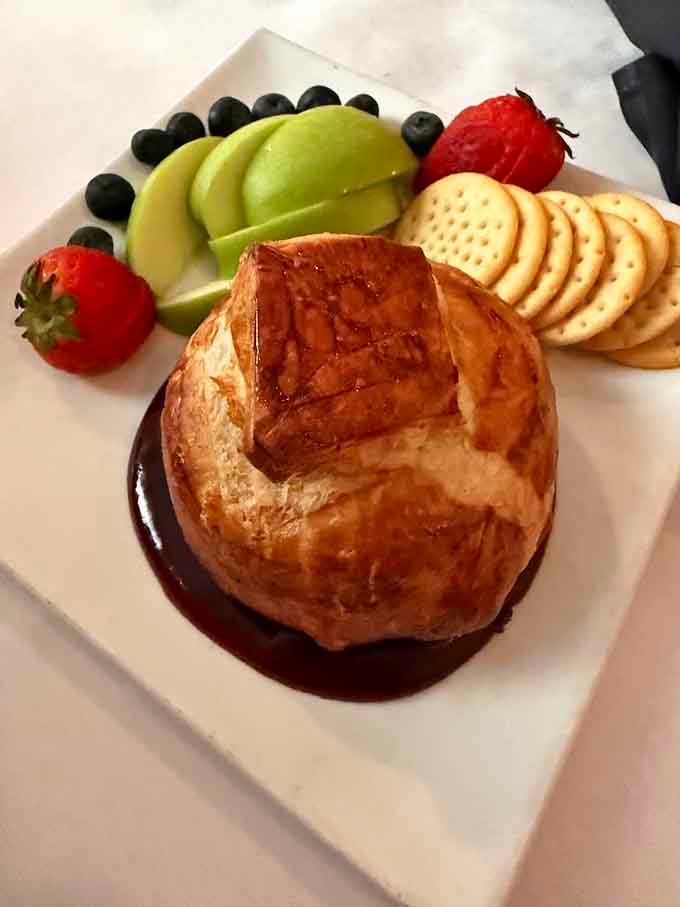 Baked brie wrapped in pastry with fruit and crackers, because sometimes elegance comes in deliciously melted packages.