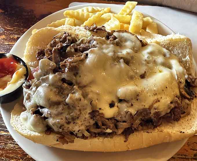 A cheesesteak piled high with meat, mushrooms, and melted cheese on a roll that's barely containing the goodness.