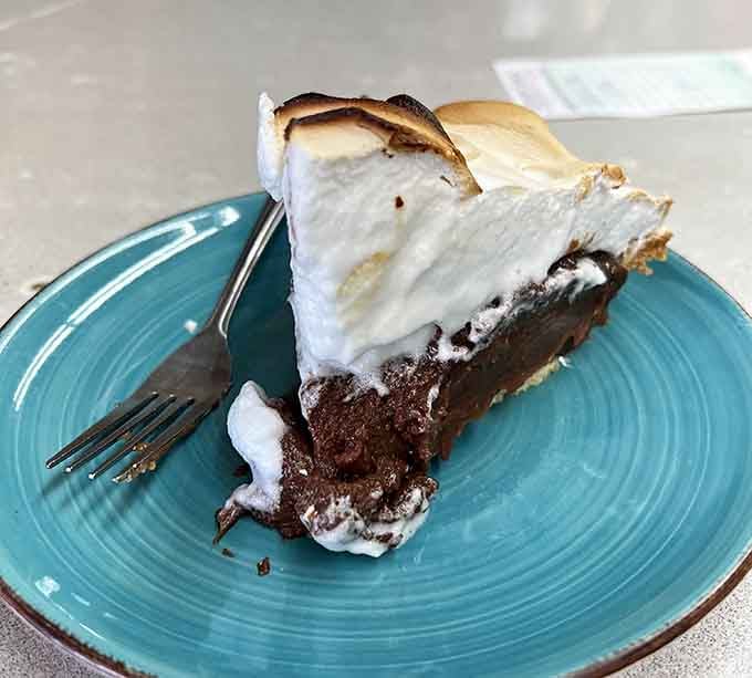 Chocolate meringue pie towering with fluffy peaks that look like edible clouds you actually want to eat.